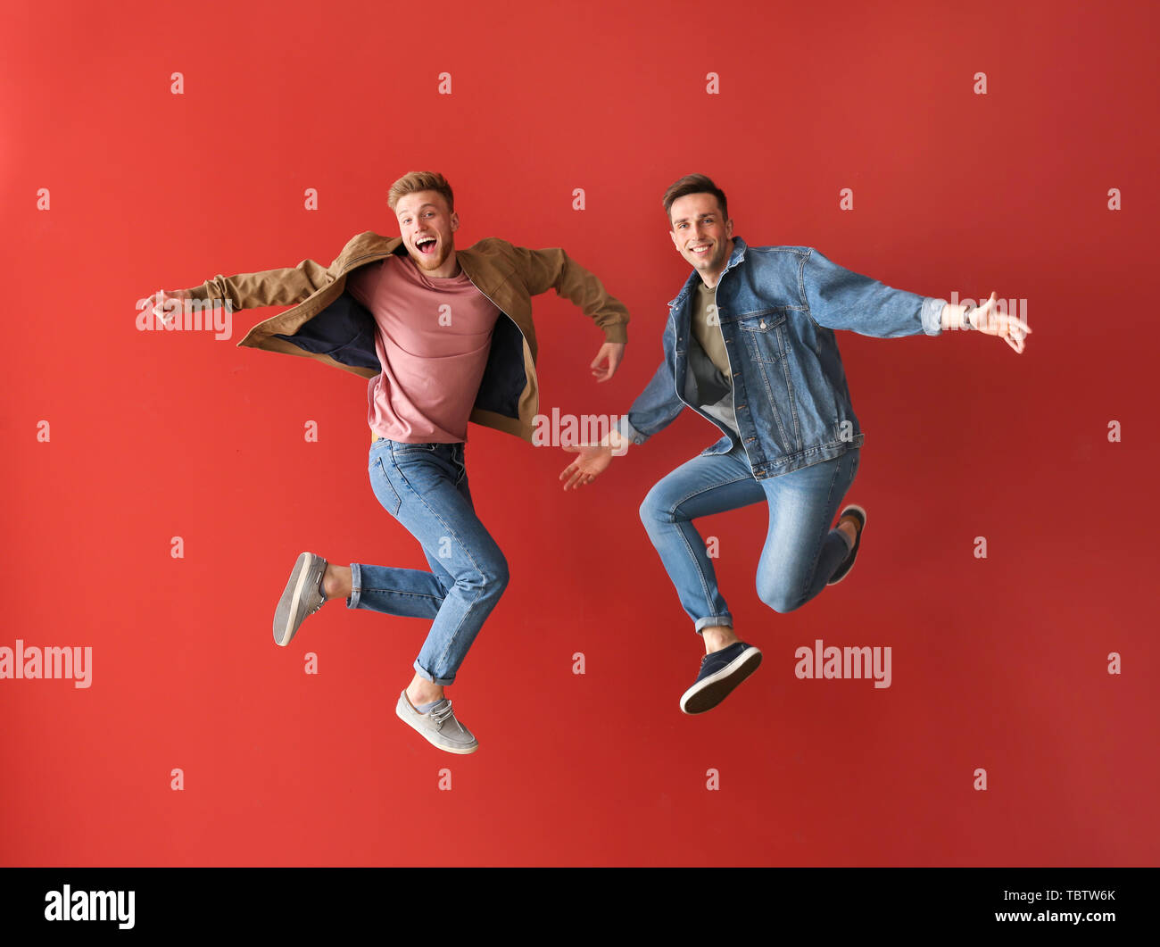 Jumping young men on color background Stock Photo - Alamy
