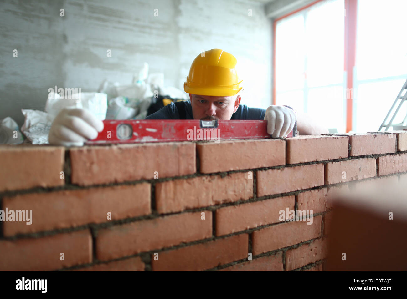 Portrait of hardworking male using level to stick to strict ...