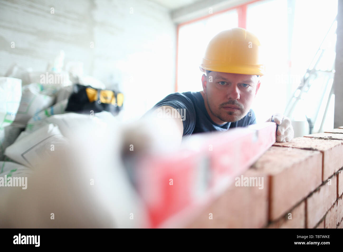 Portrait of skilled professional bricklayer using special equipment and ...