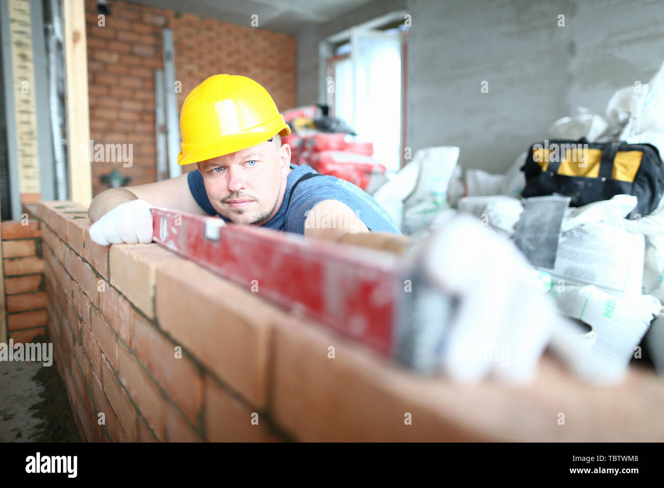 Portrait of smart builder using special red tool to measure level of ...