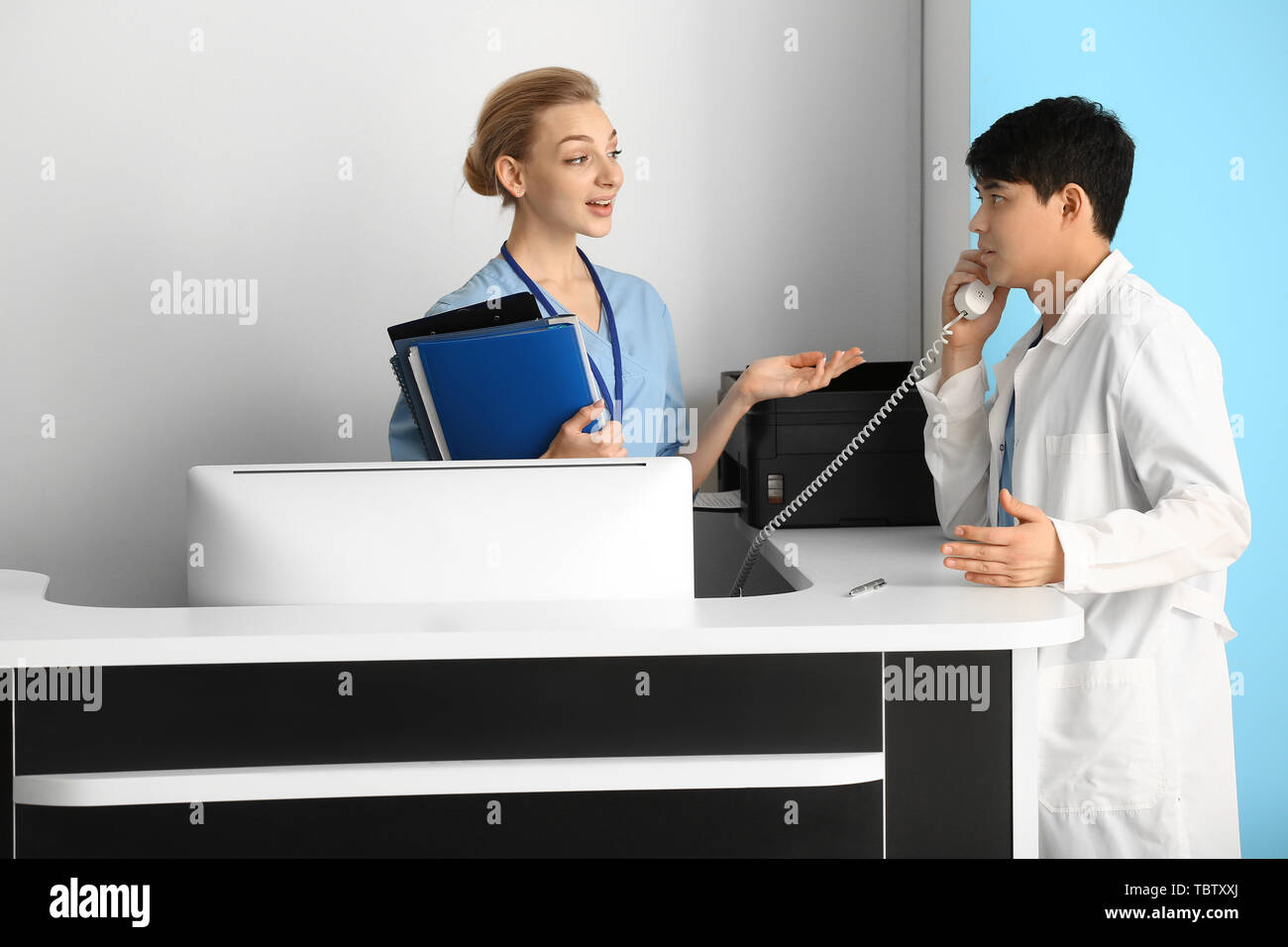 Male doctor talking by phone near reception desk in clinic Stock Photo ...