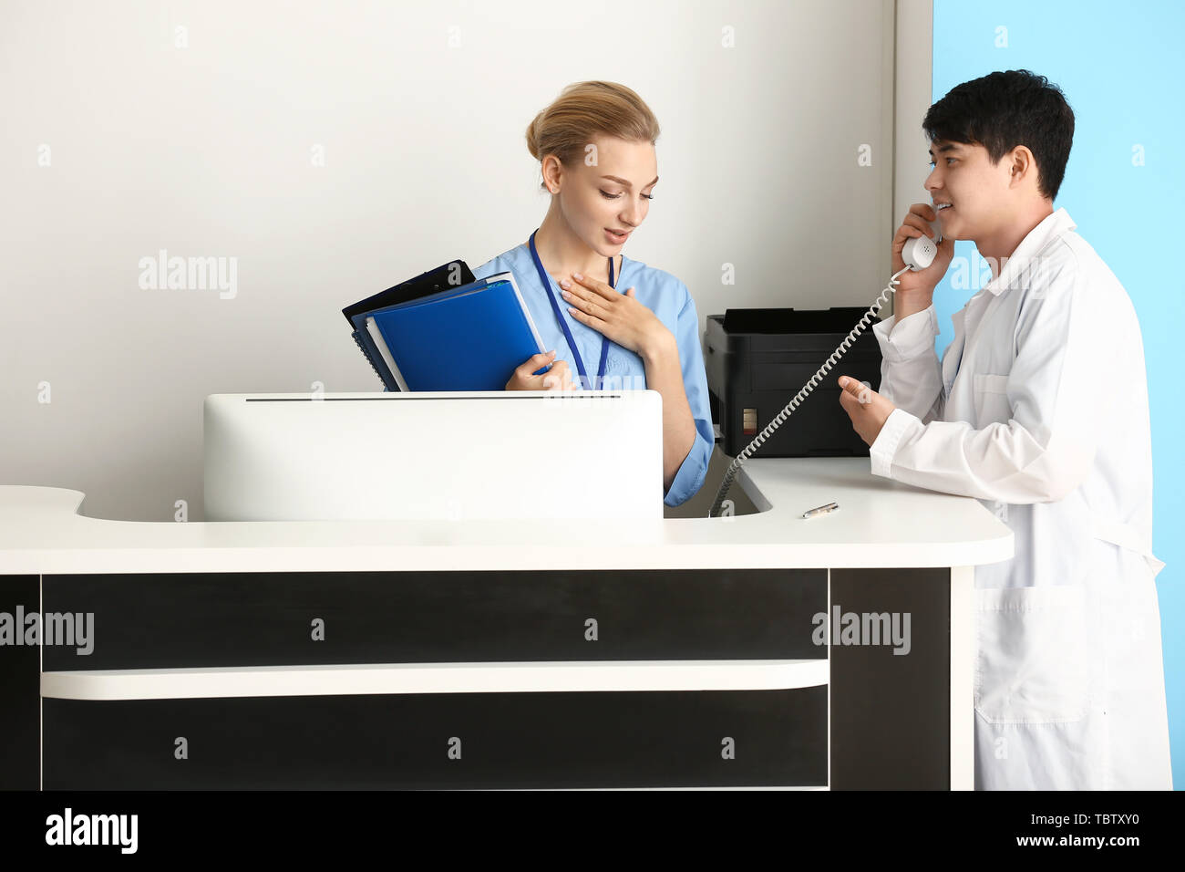 Male doctor talking by phone near reception desk in clinic Stock Photo ...