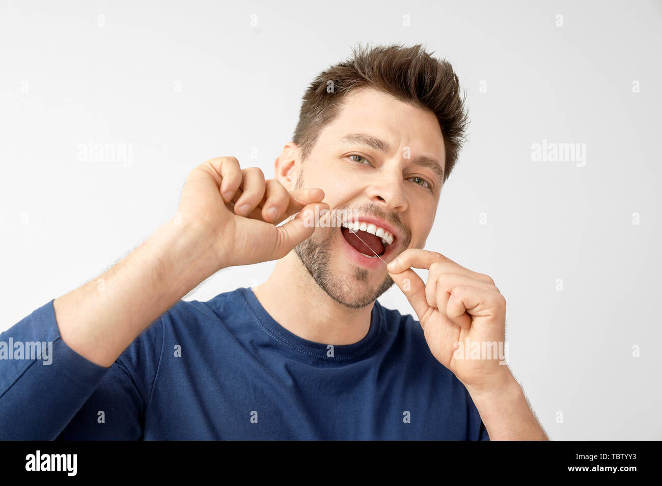 Man flossing teeth on light background Stock Photo - Alamy