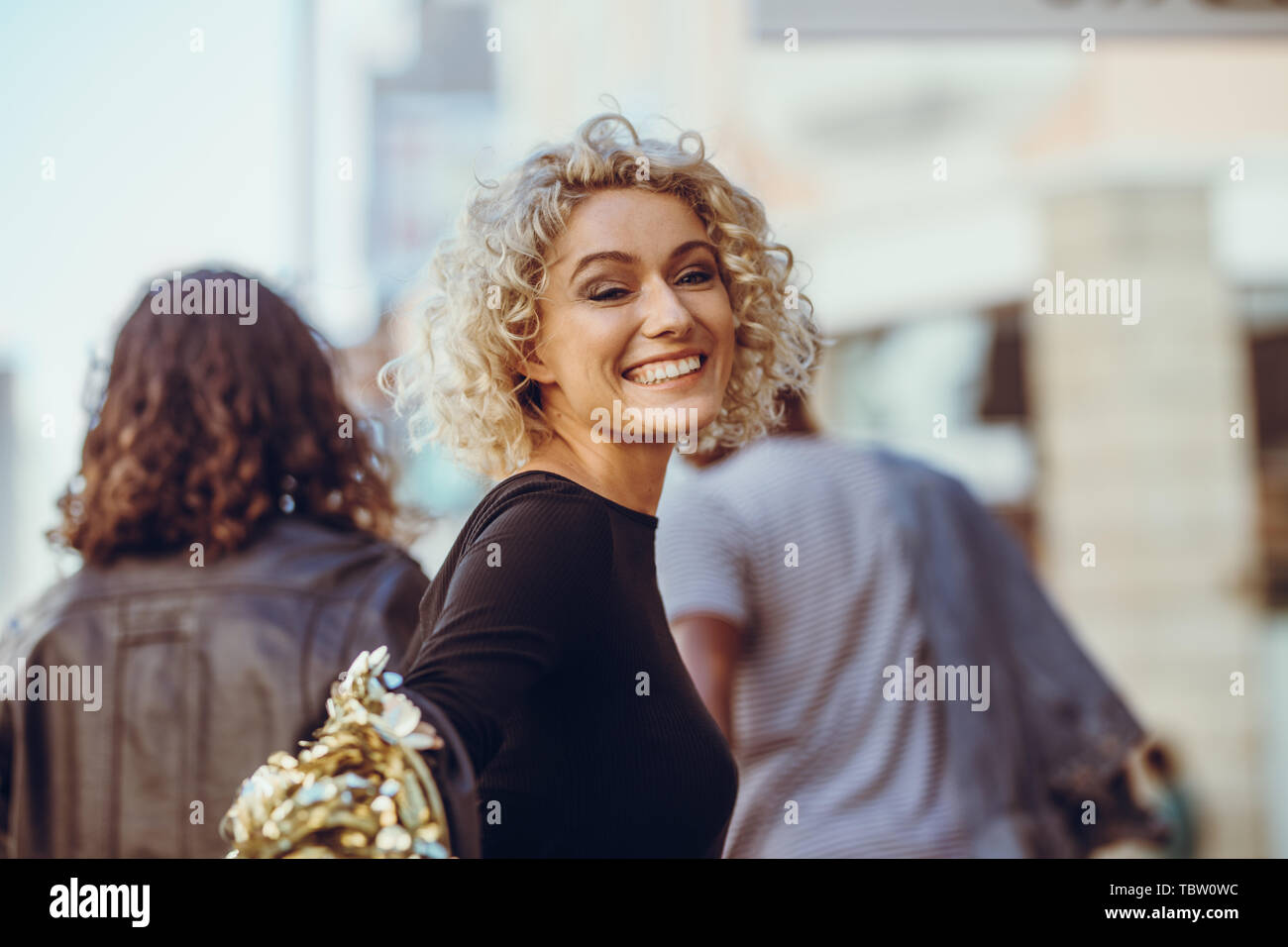 Rear view of cheerful young woman looking back while walking in the ...