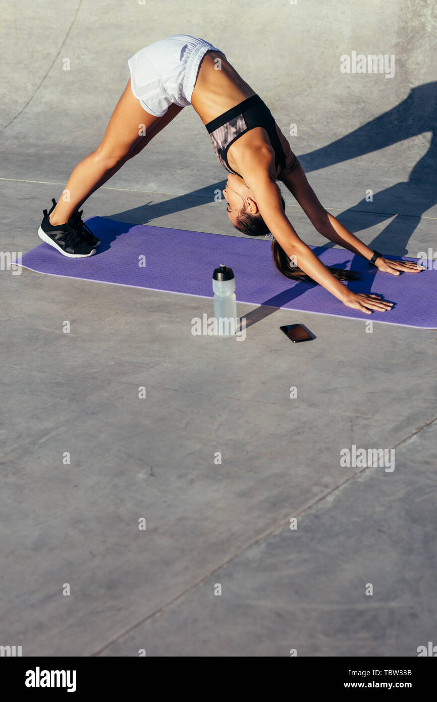 Flexible young woman practising downward facing dog yoga pose. Woman in ...