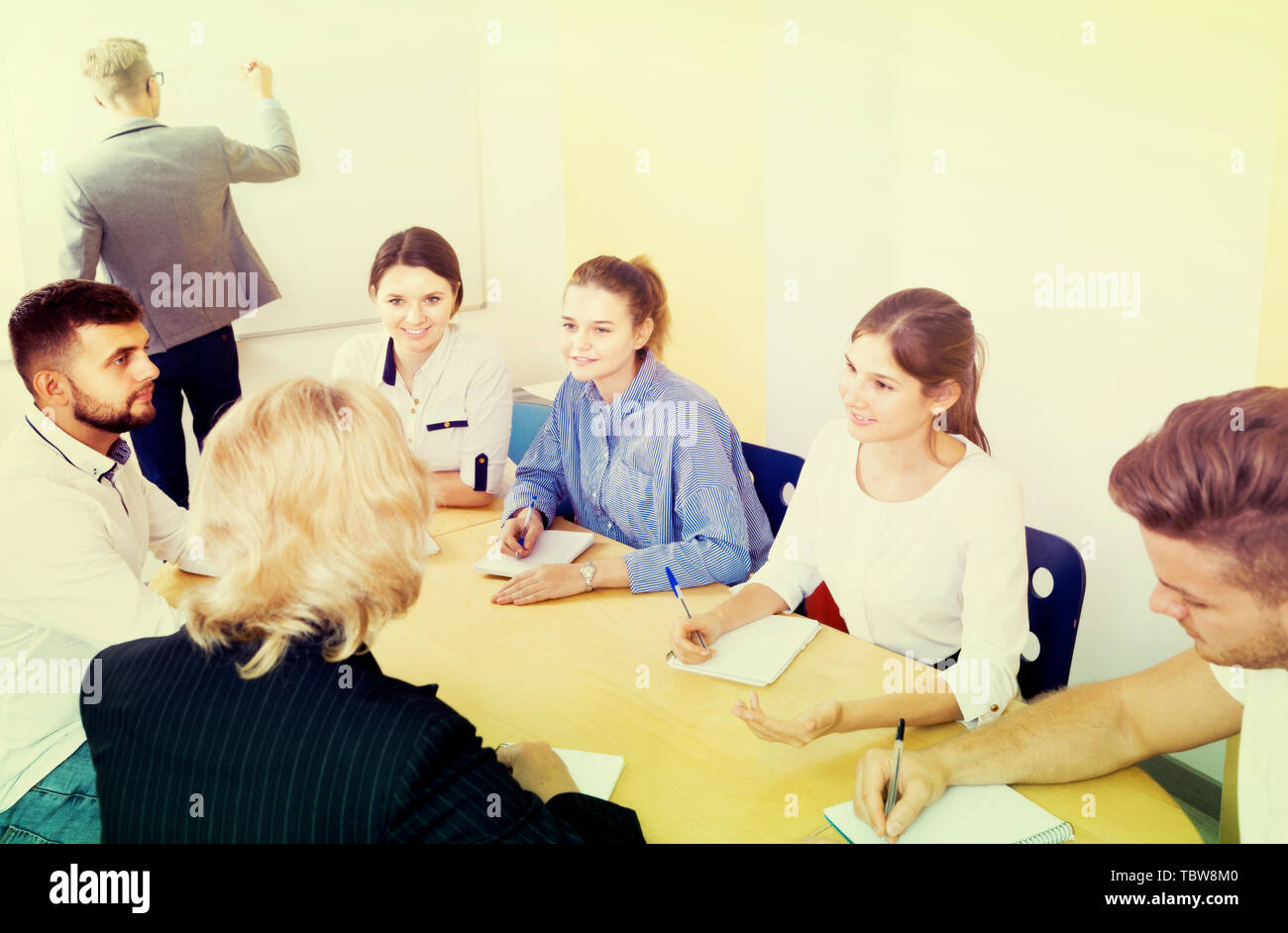 Students of different age doing group brainstorming in classroom while ...