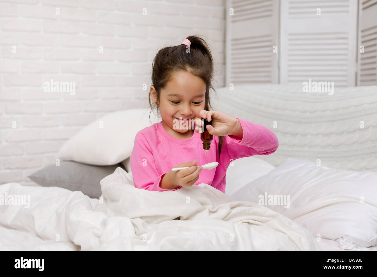 Sick little child girl pouring antipyretic syrup for kid in bed Stock ...