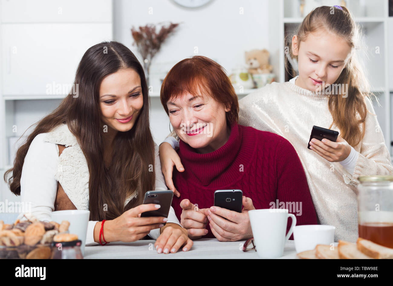 Modern grandmother with adult daughter and granddaughter, sitting with ...