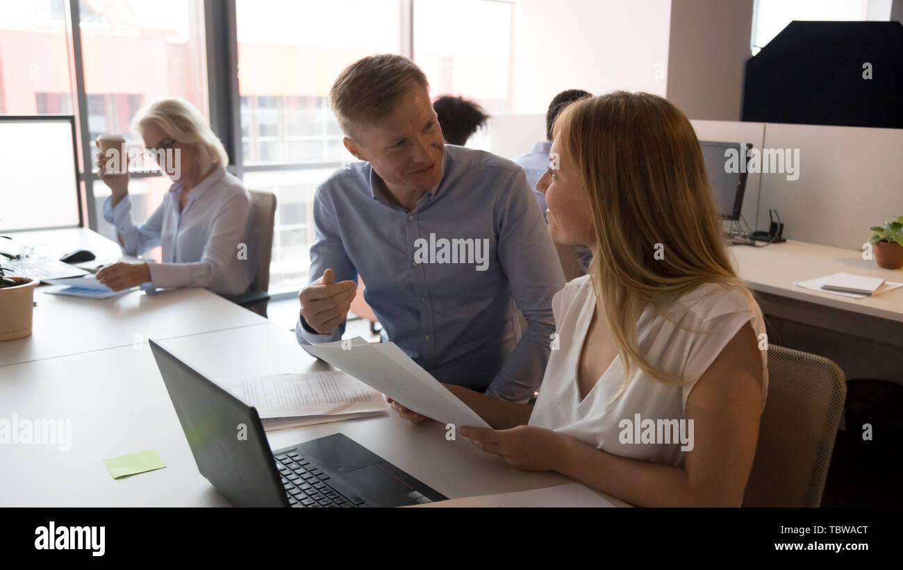 Confident businessman mentor helping female intern with paperwork Stock ...