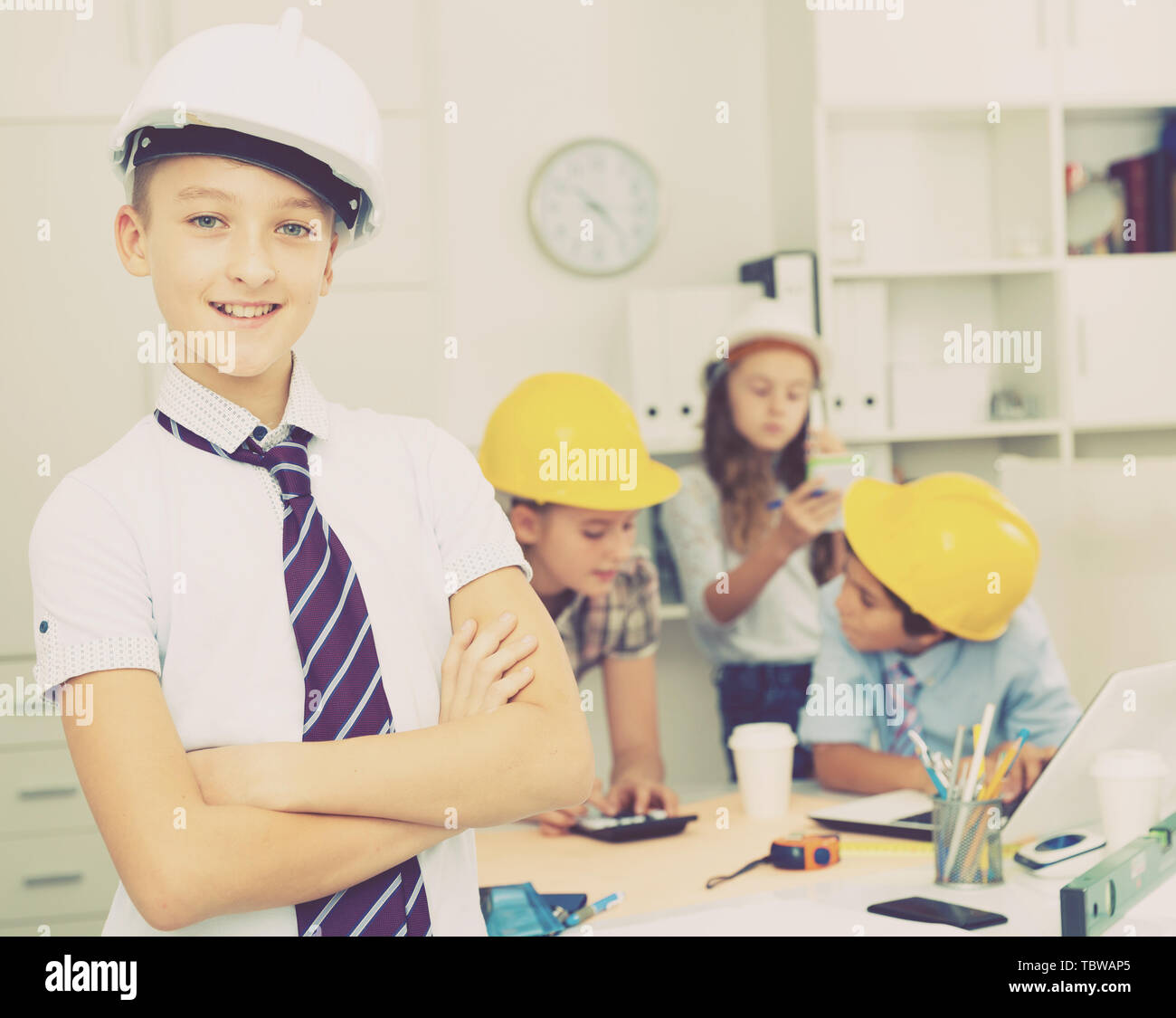 Portrait of boy in helmet and tie with group of children architects ...