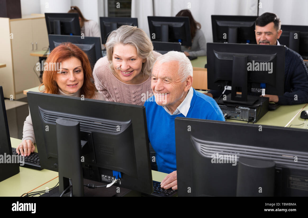 Three coworkers working around computer monitor, talking about new ...