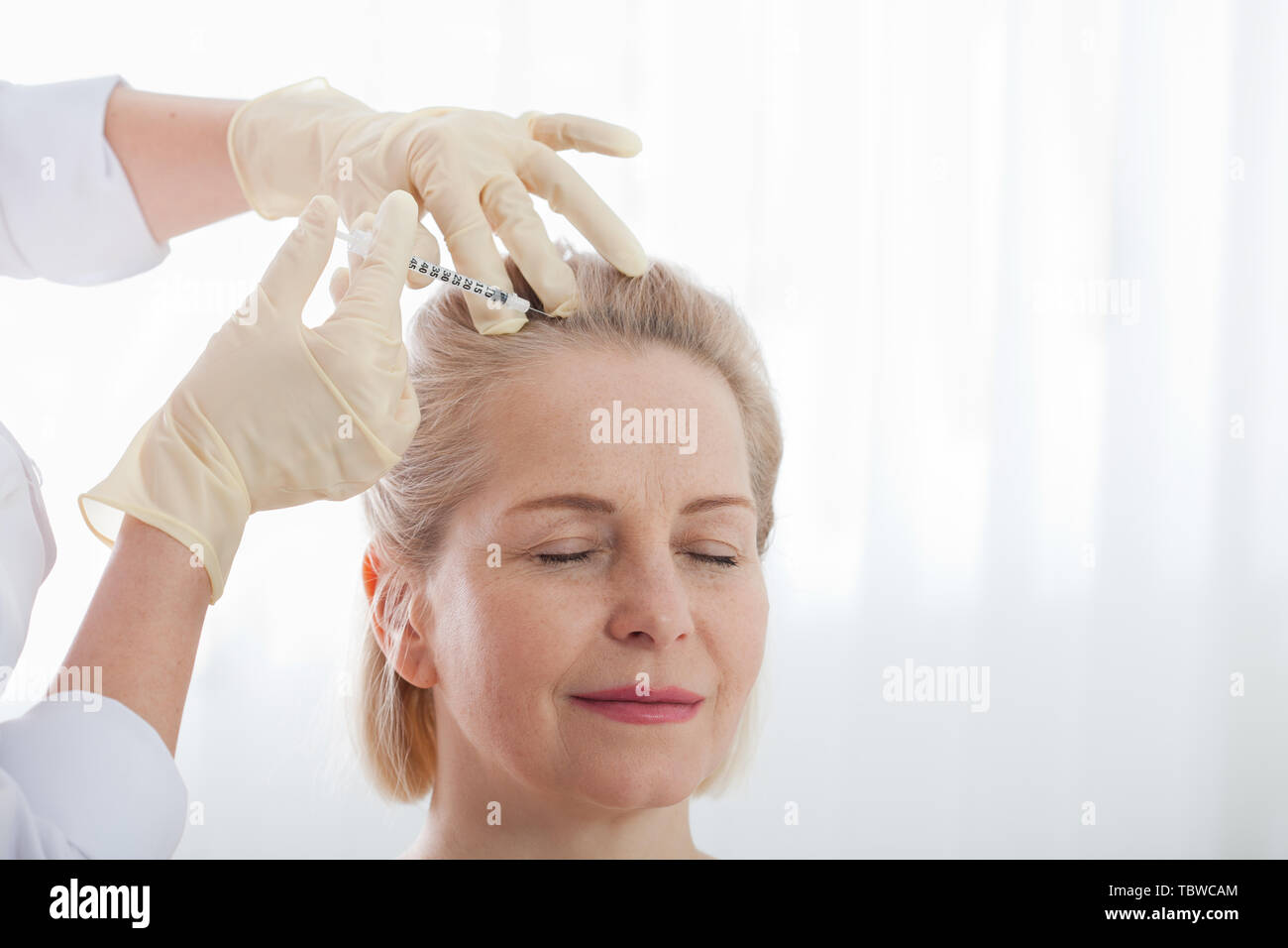 Middle aged woman gets cosmetic injection in her forehead. Hyaluronic ...