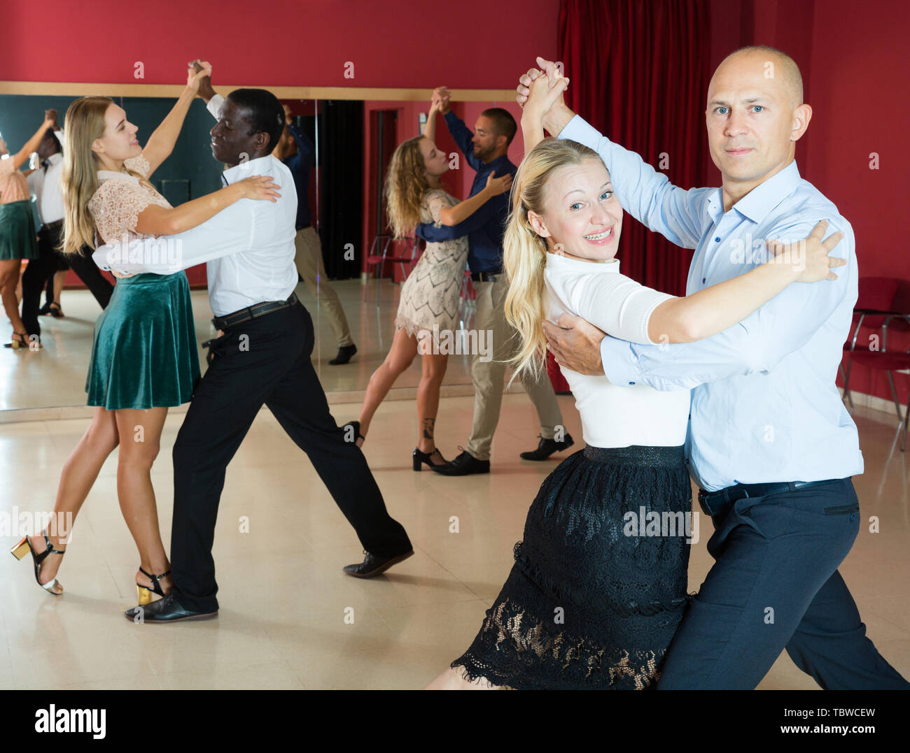 Portrait of positive adult couples dancing tango together in modern studio Stock Photo - Alamy