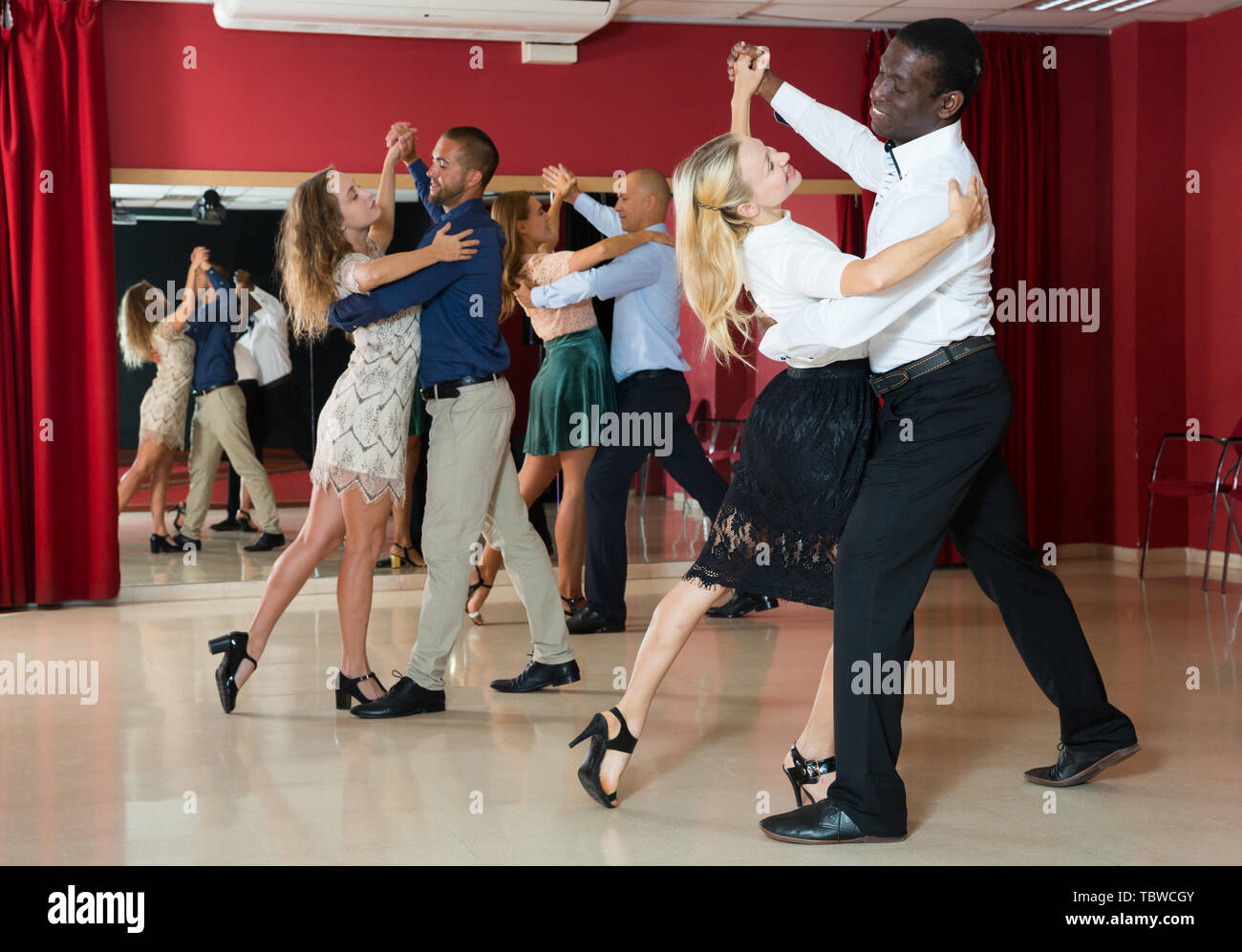 Young positive people dancing together slow ballroom dances in pairs ...