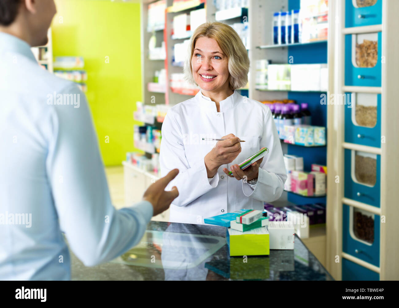 Friendly positive female pharmacist counseling customer about drugs ...