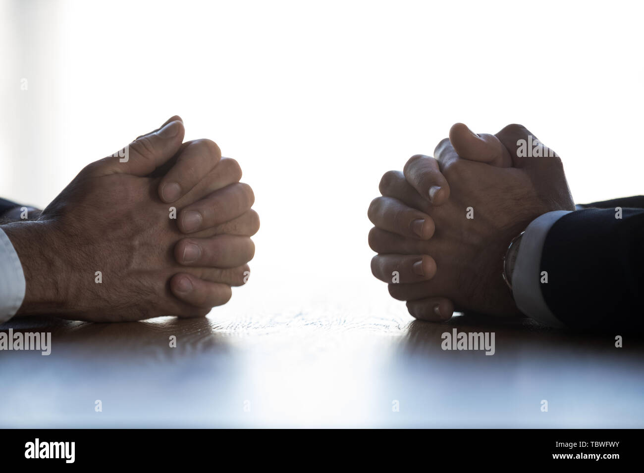 Close up of businessmen sit at table with hands clenched Stock Photo ...