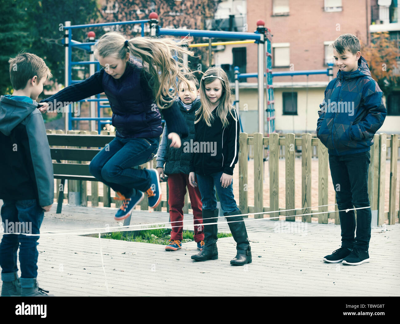 positive russian kids skipping on chinese jumping elastic rope in yard ...