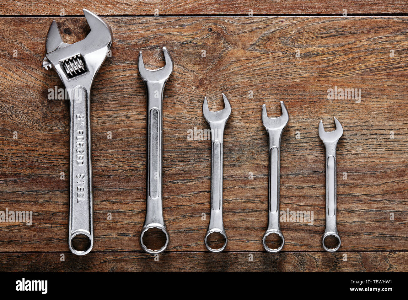 Set of wrenches tiered on wooden table background. Top down view with ...