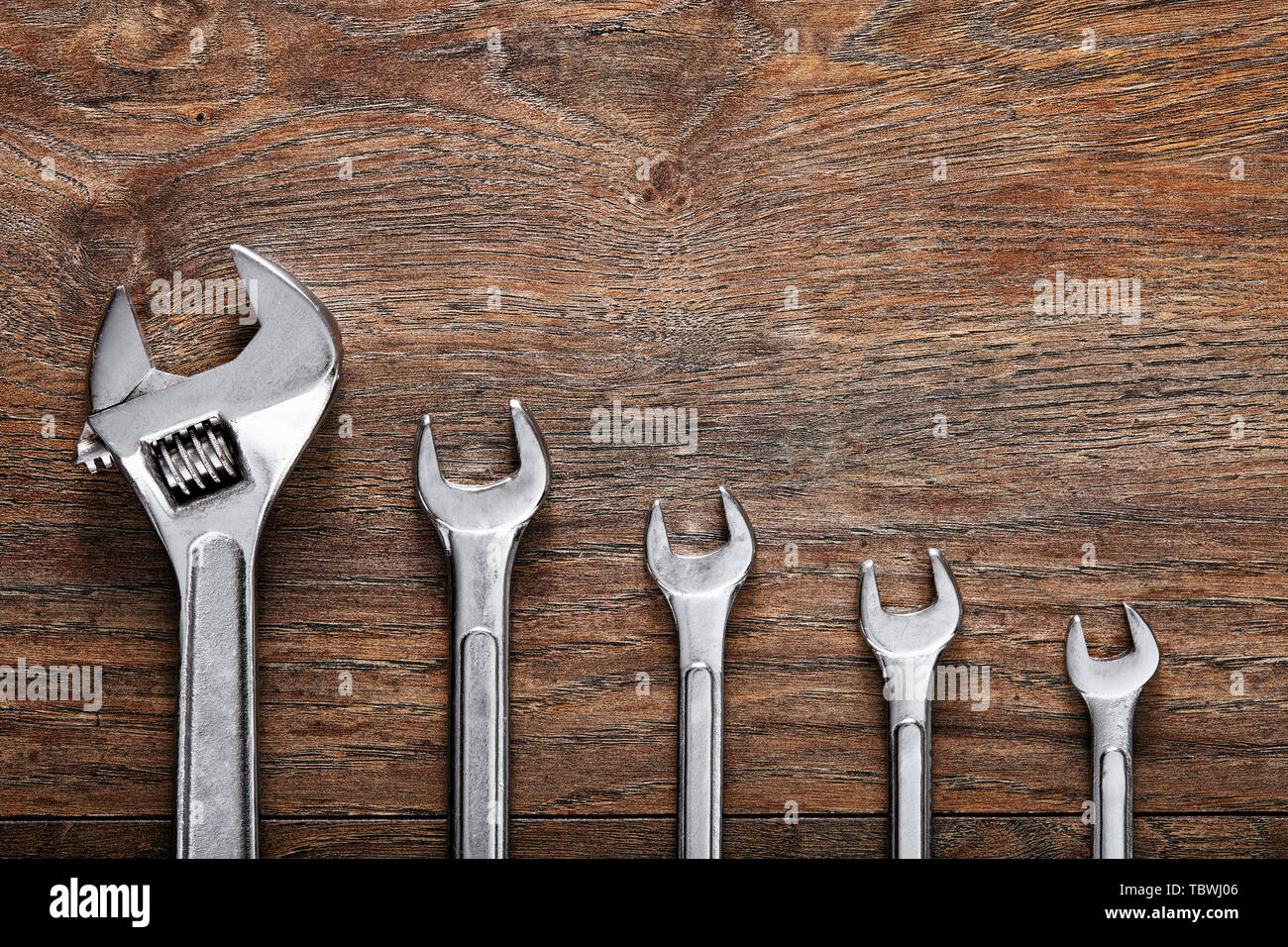 Set of wrenches tiered on wooden table background. Top down view with ...