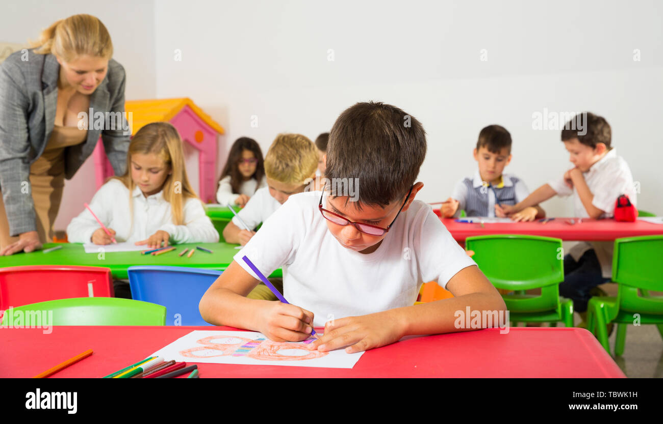 Portrait of boy student of primary school doing his task at desk in ...