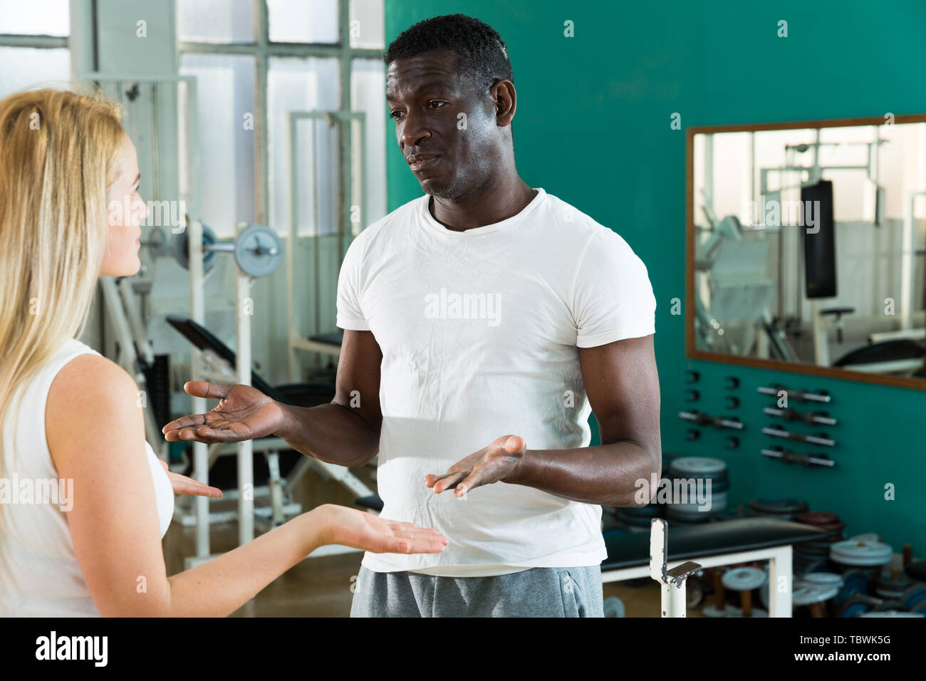 Positive man and woman in sportswear having conversation at sport club ...
