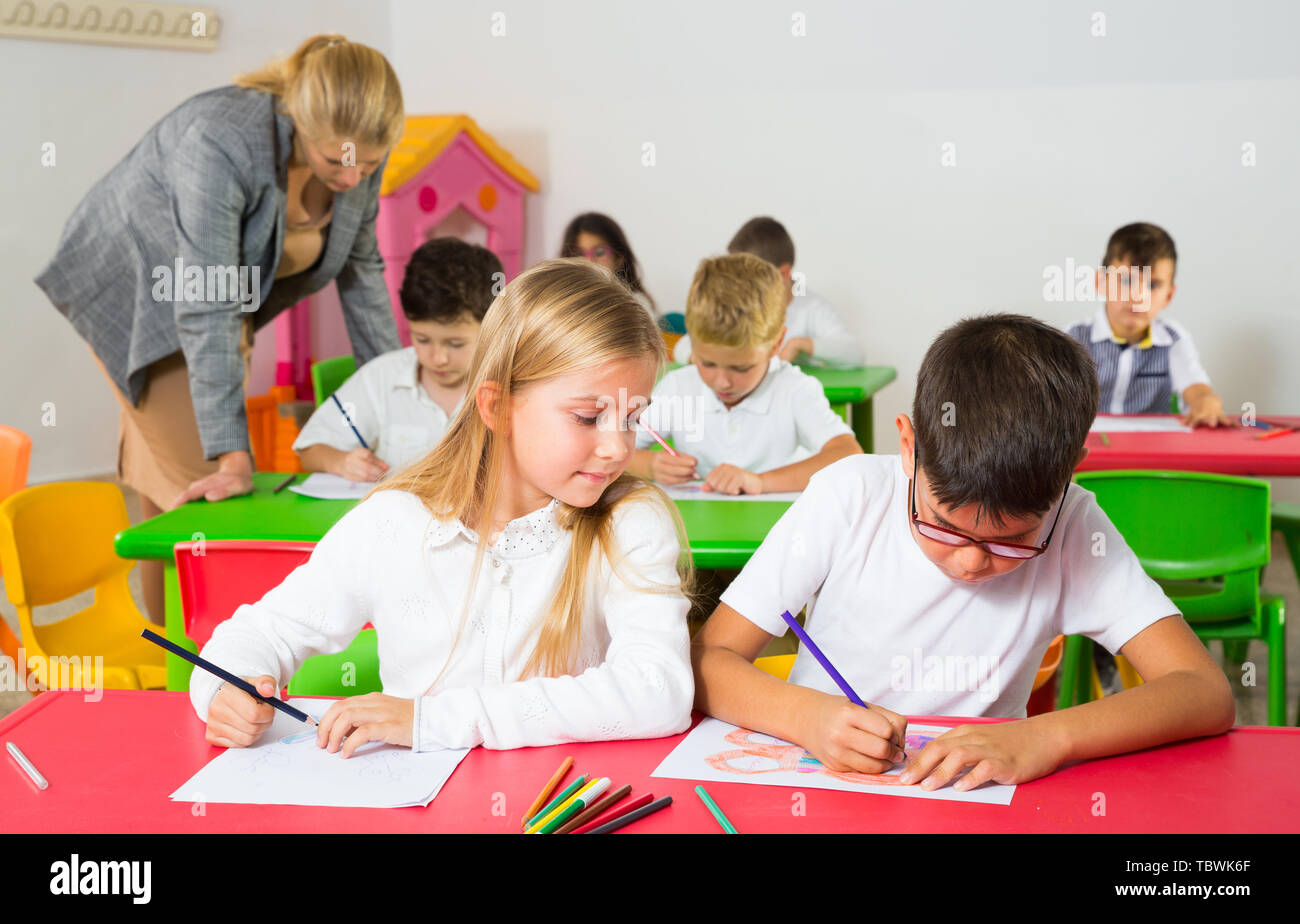 Portrait of children discussing theirs drawings during lesson in school ...