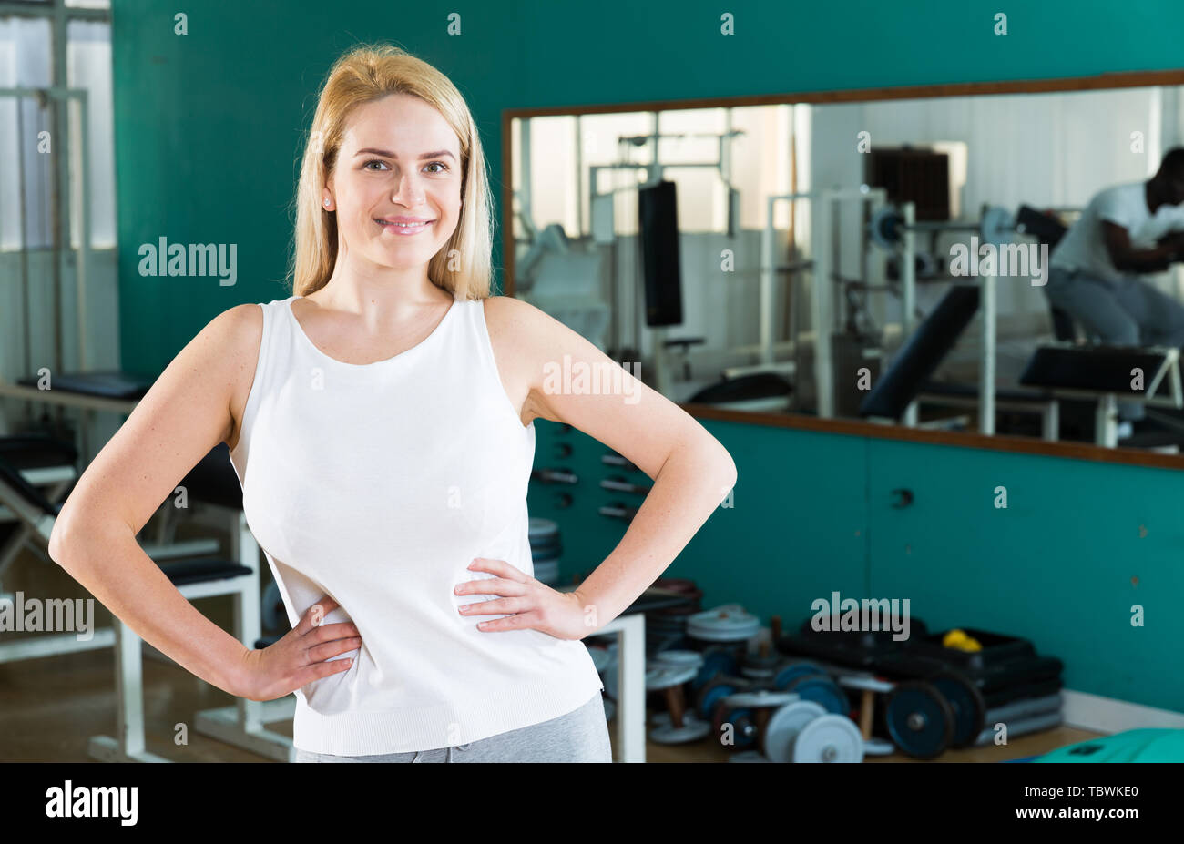 Portrait of positive friendly girl welcoming to gym with exercising man ...