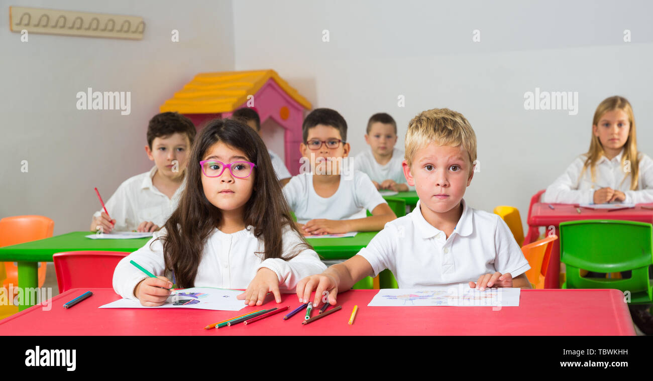 Portrait of surprised little pupils at lesson in classroom at ...