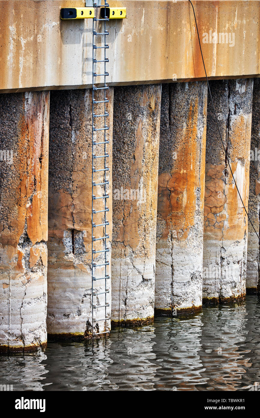 Metal climbing ladder mounted on the concrete columns of a harbor Stock ...