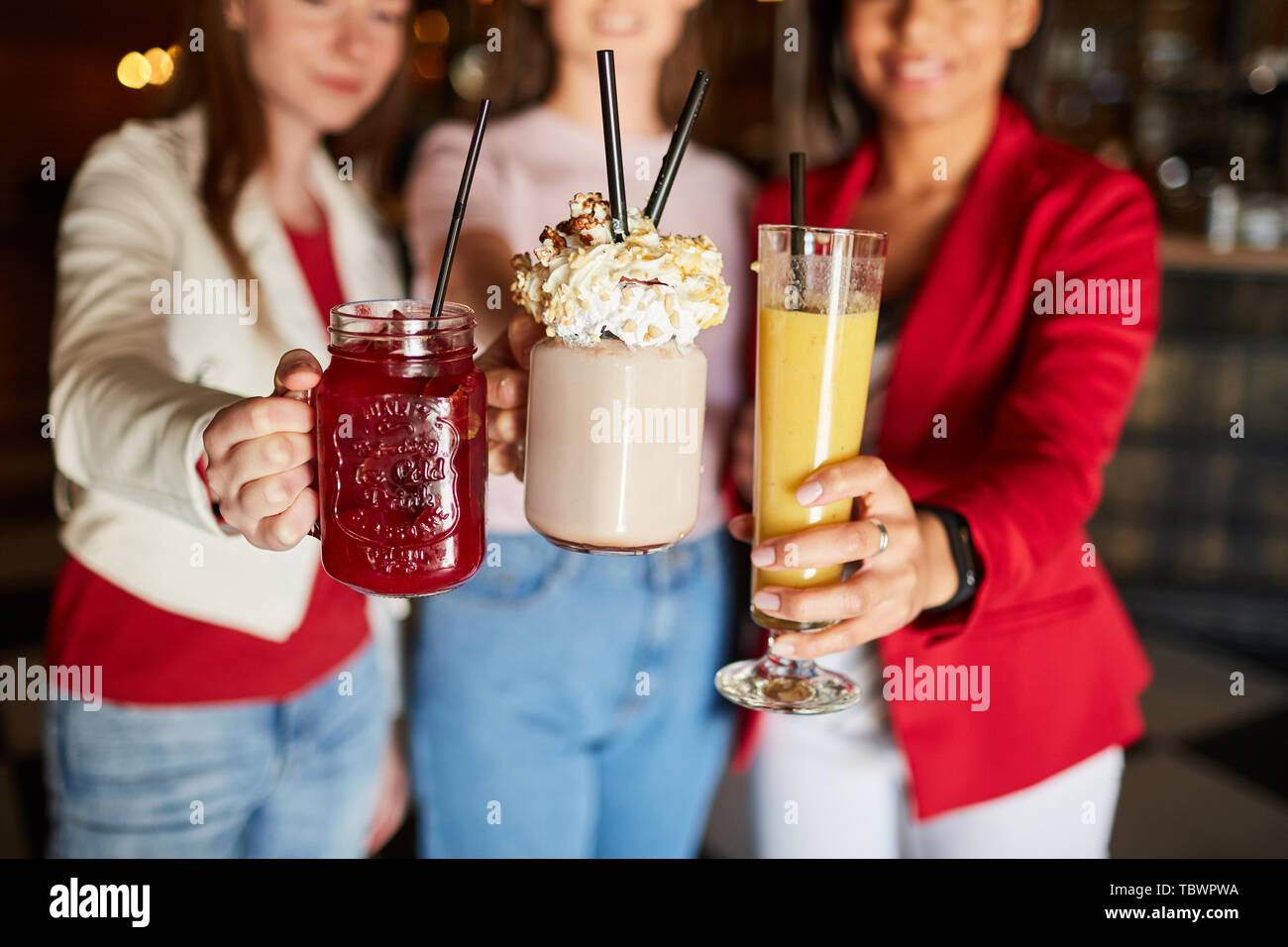 Close-up of young women reaching hands with refreshing cocktails for ...
