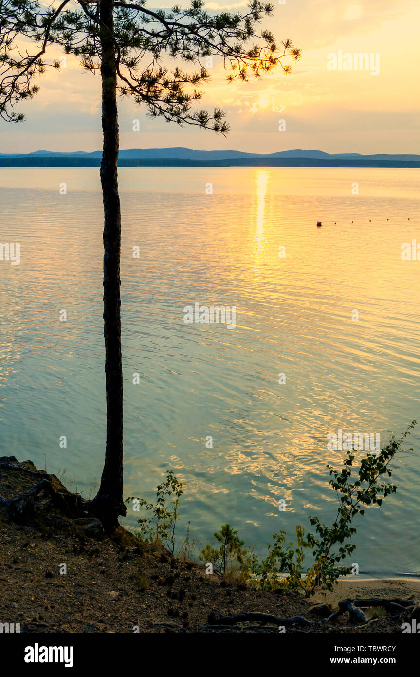 Summer sunset landscape. Stone cliff and lake lit by golden sunset ...