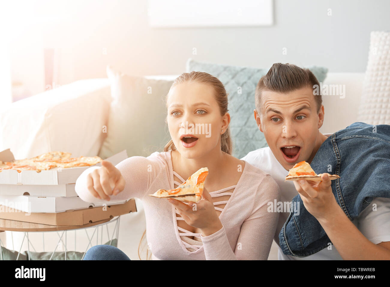 Emotional couple eating tasty pizza while watching TV at home Stock ...