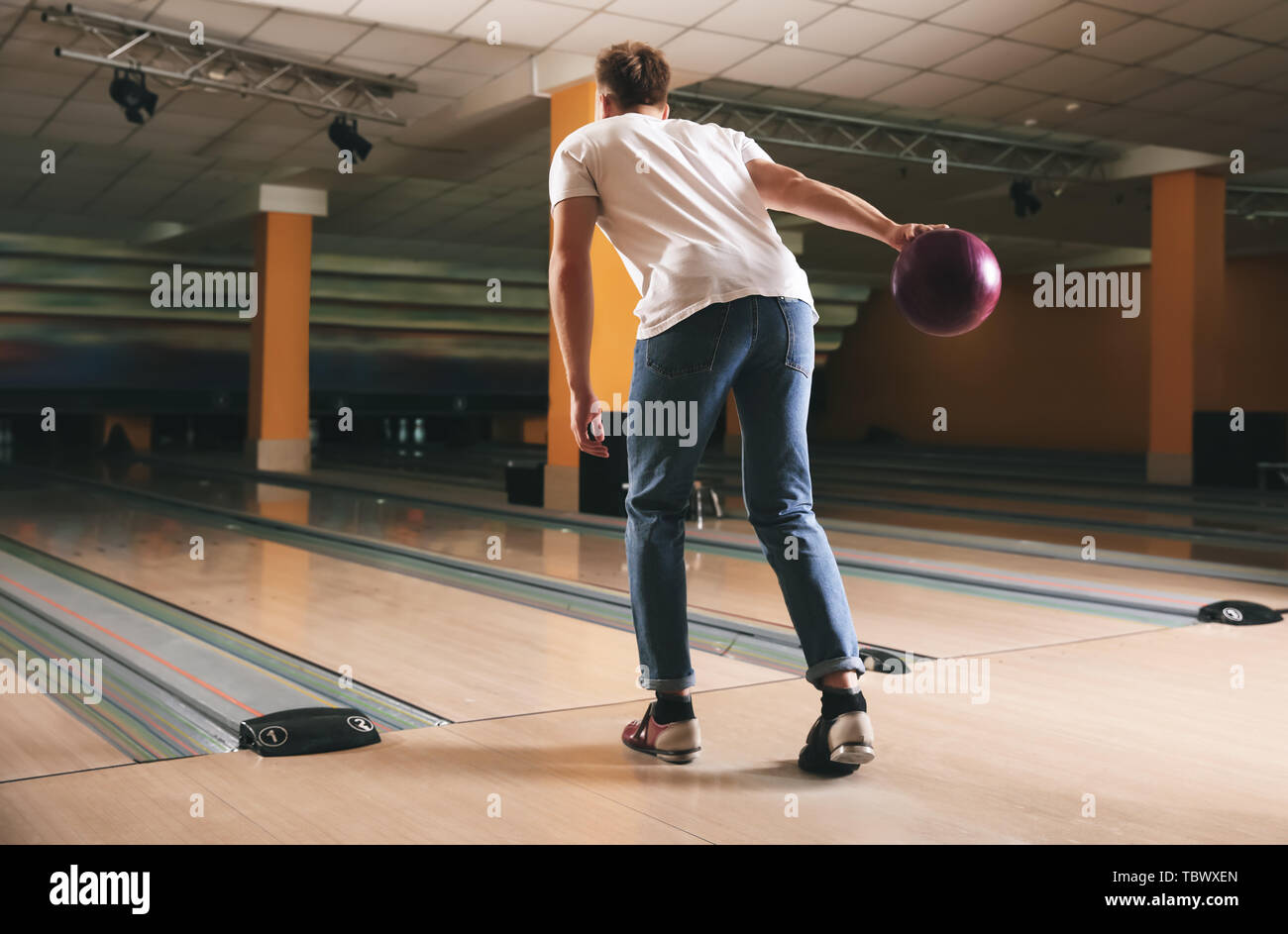 Young man playing bowling in club Stock Photo - Alamy