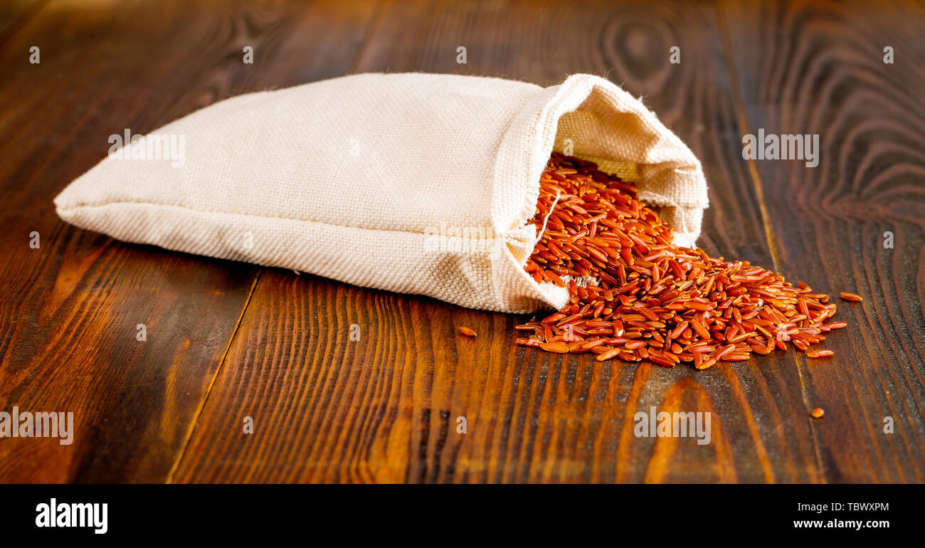 Bag with red Cargo rice on wooden surface Stock Photo - Alamy