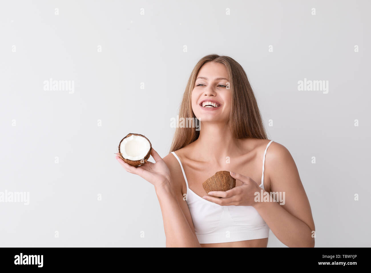 Beautiful young woman with coconut on light background Stock Photo - Alamy