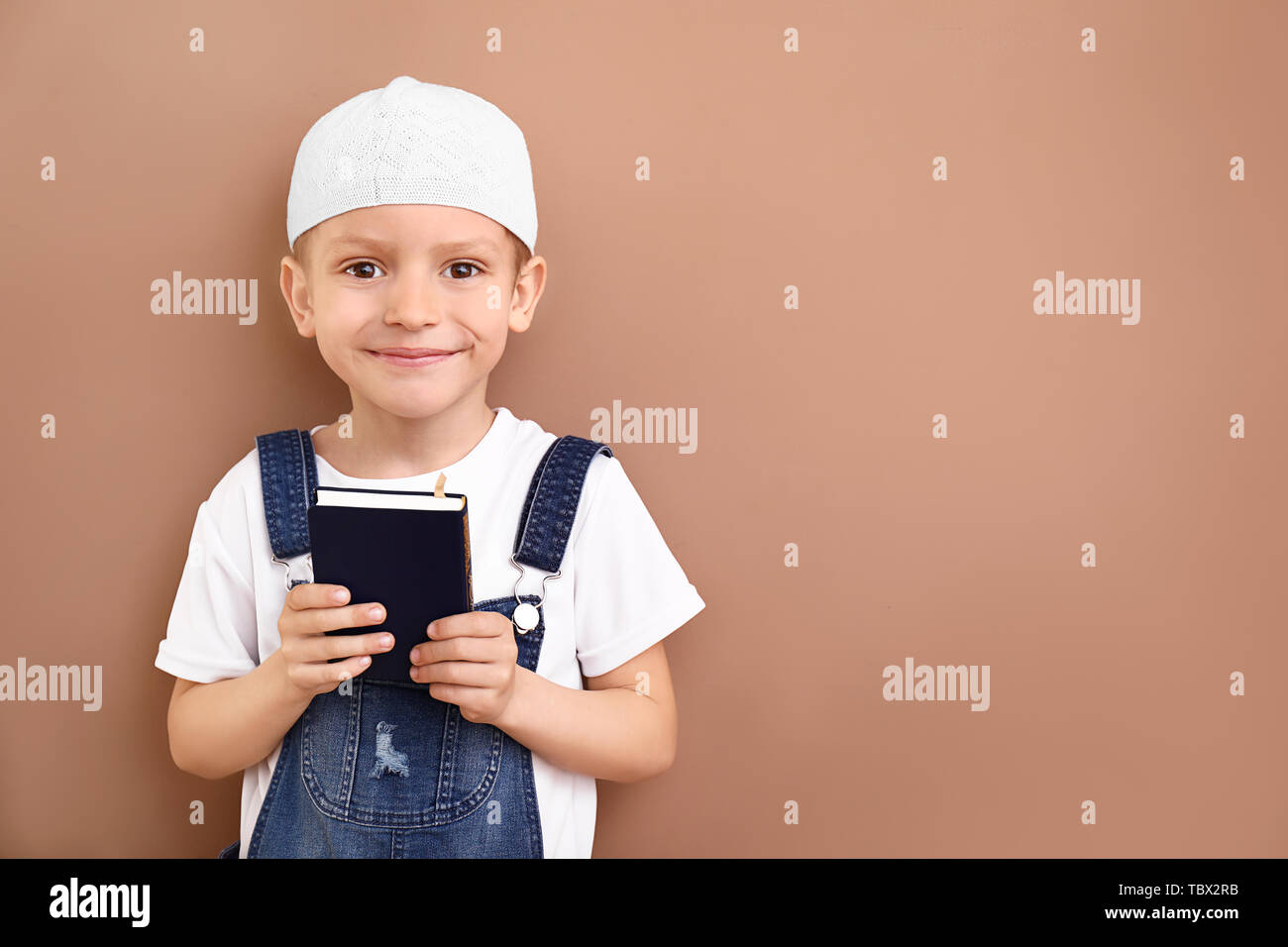 Little Muslim boy with Koran on color background Stock Photo - Alamy