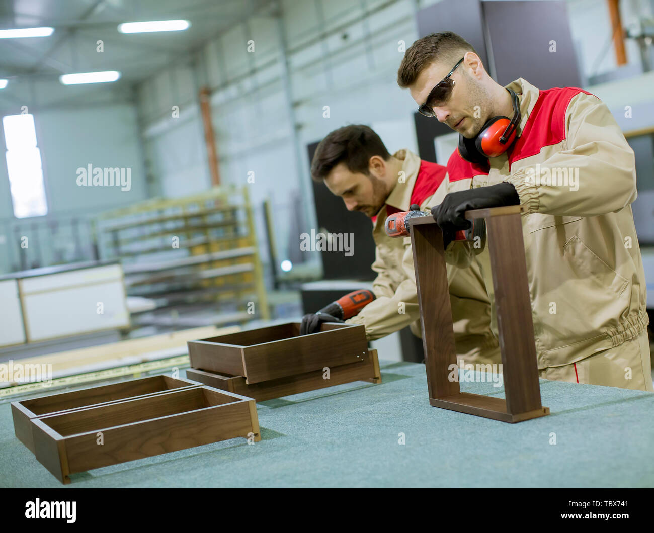 Two handsome young workers assembling furniture in the factory Stock ...