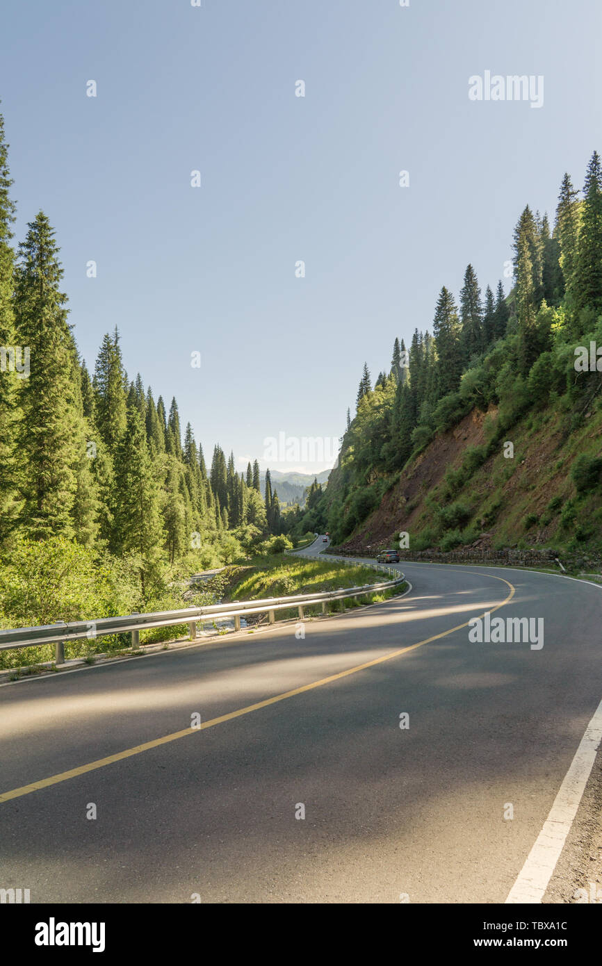 G217 Duku Highway bend in alpine forest under summer blue sky and white ...