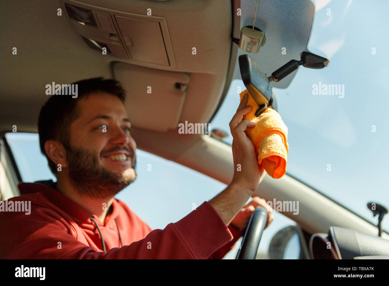 Happy man with orange rag washing mirror machine Stock Photo - Alamy