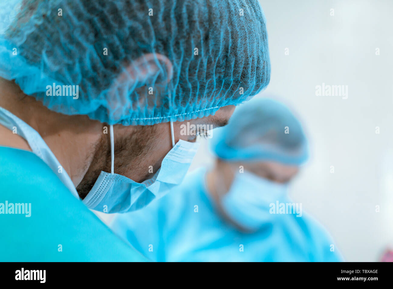 An experienced surgeon in a mask and gown operates in a sterile ...