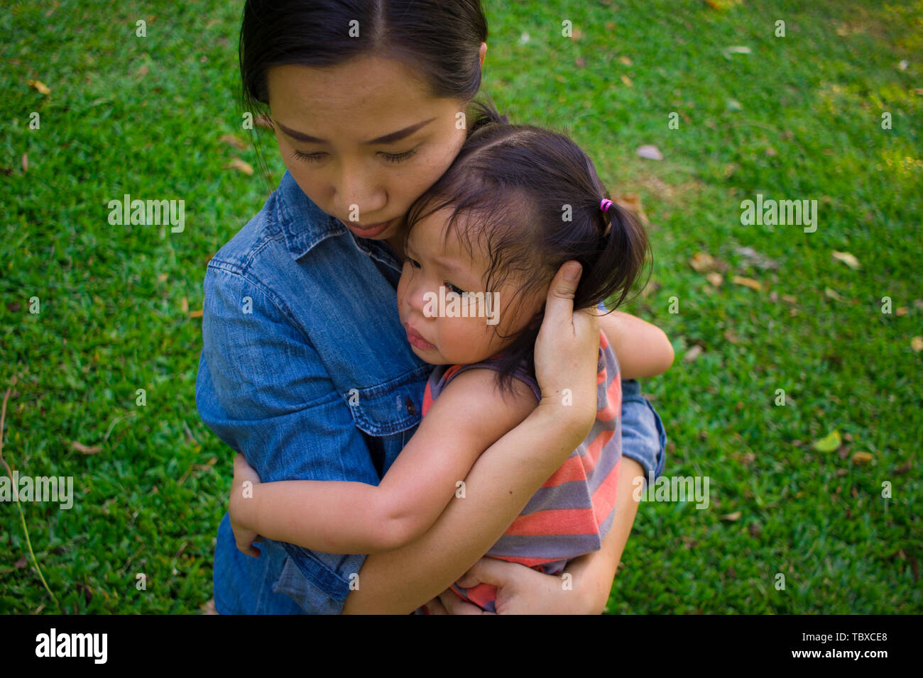 Young mother hugging and soothing a crying little daughter, Asian ...