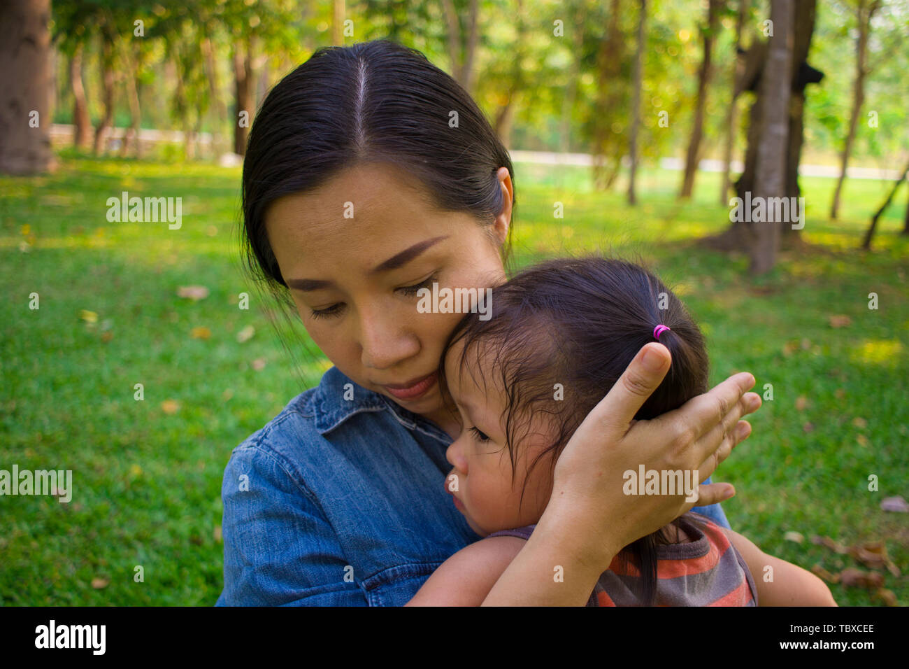 Young mother hugging and soothing a crying little daughter, Asian ... Young mother hugging and soothing a crying little daughter, Asian ...