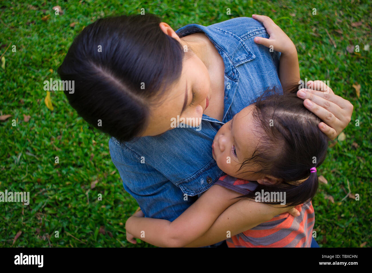 Young mother hugging and soothing a crying little daughter, Asian ...
