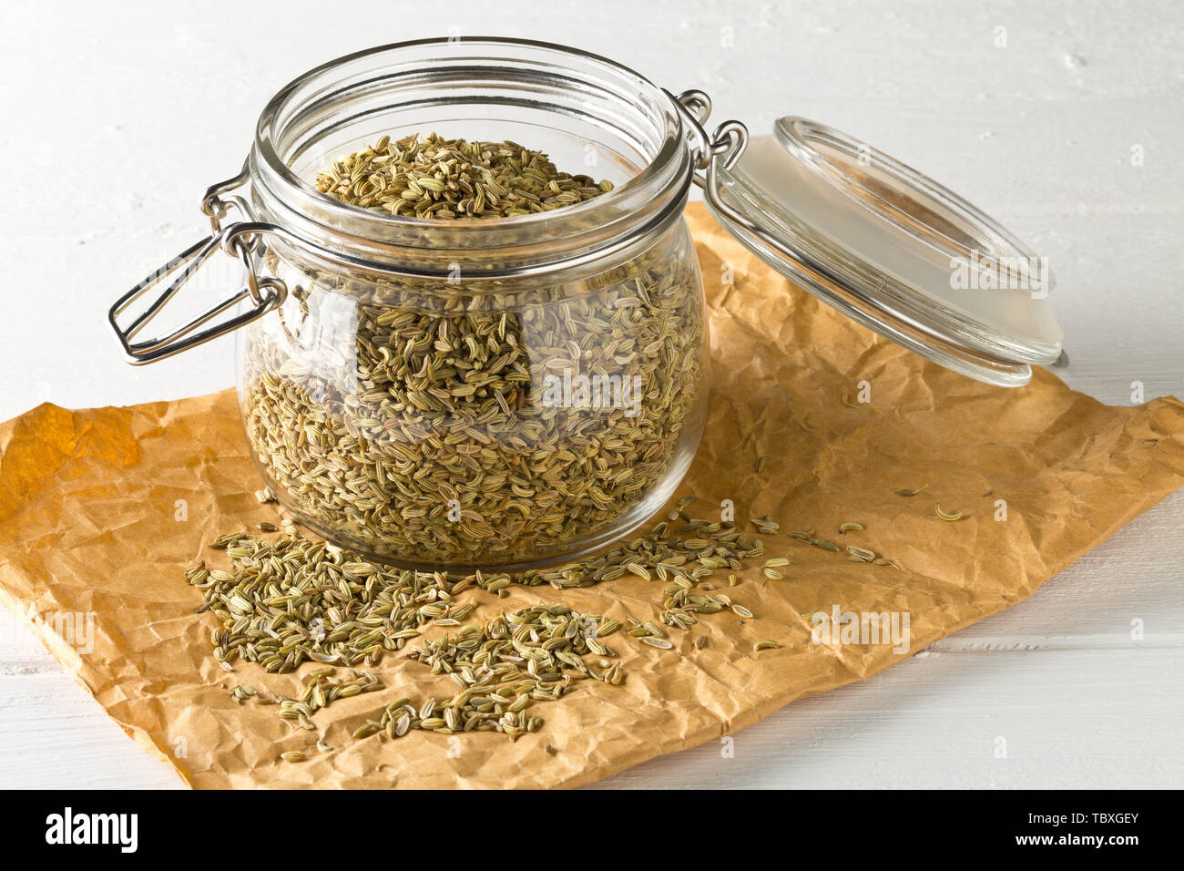 Dried fennel seeds in glass storage jar on white wooden table ...