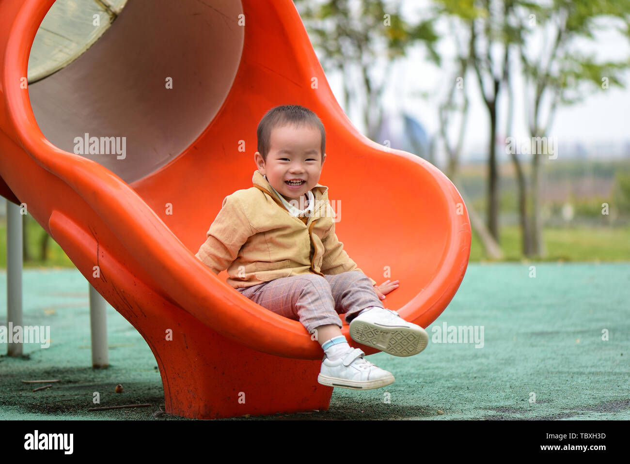 A little baby playing on a slide in a playground Stock Photo - Alamy