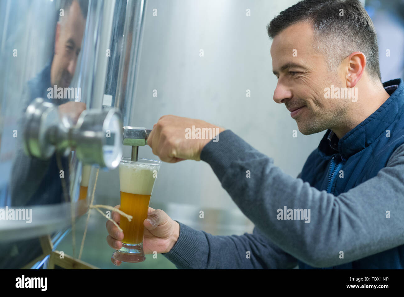 brewer filling glass of beer from vat Stock Photo - Alamy