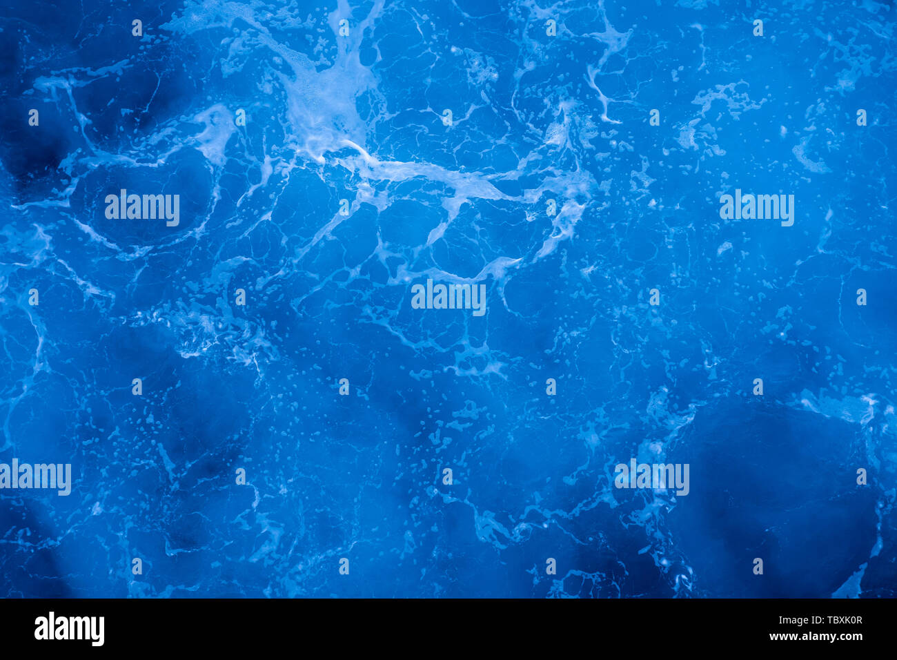 Dark blue deep sea surface, rippled water with sea foam and sparkling ...