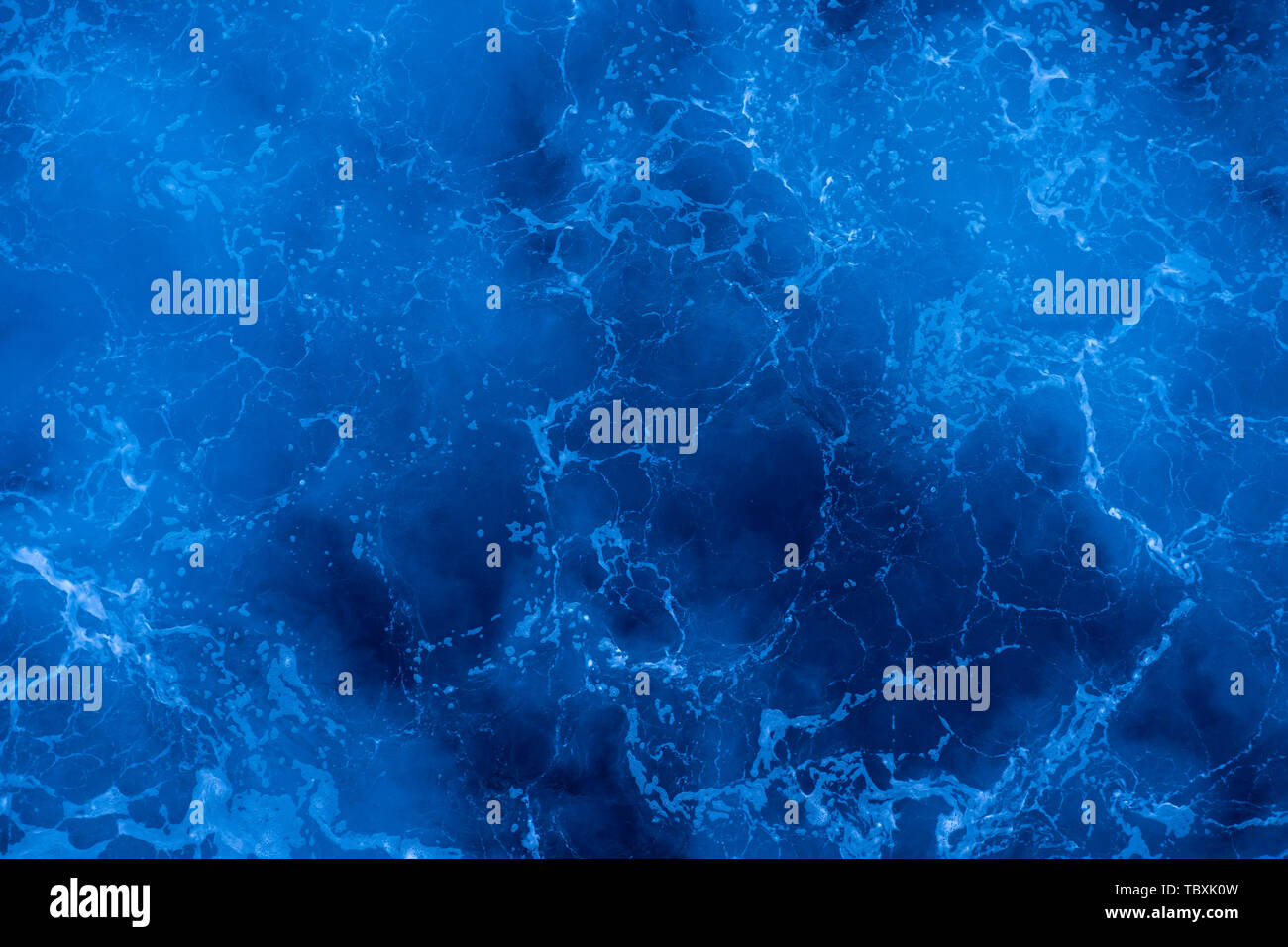 Dark blue deep sea surface, rippled water with sea foam and sparkling ...