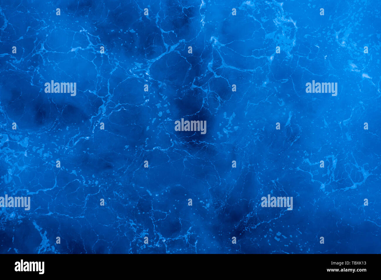 Dark blue deep sea surface, rippled water with sea foam and sparkling ...