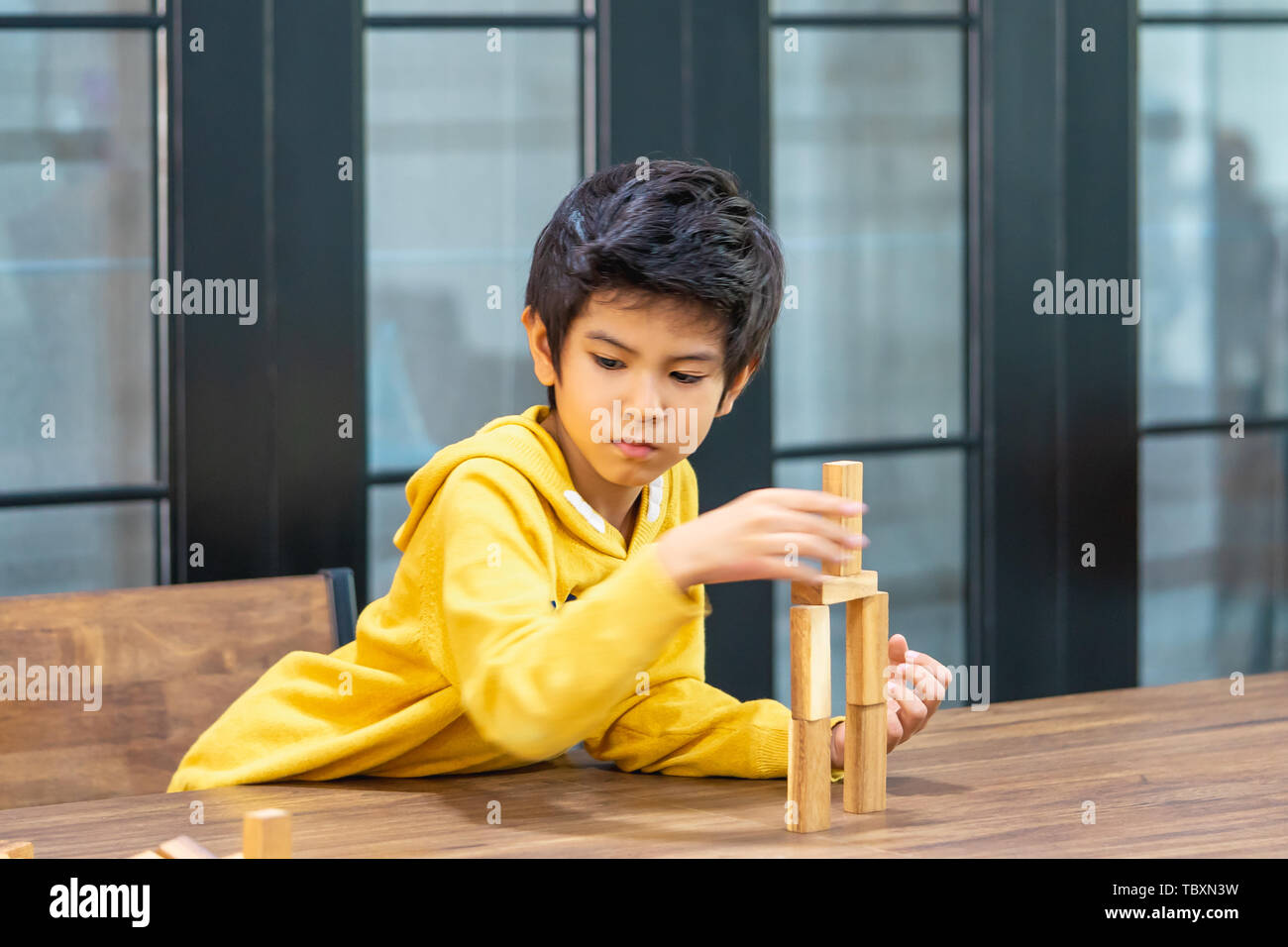 Little Boy is building wooden toy block tower Stock Photo - Alamy